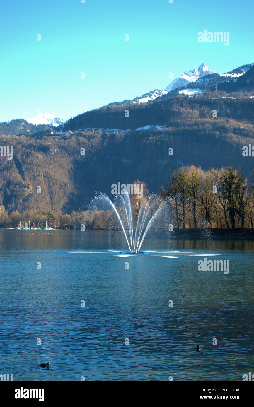 Splashing water fountain and an alpine scenery at the Walensee in ...