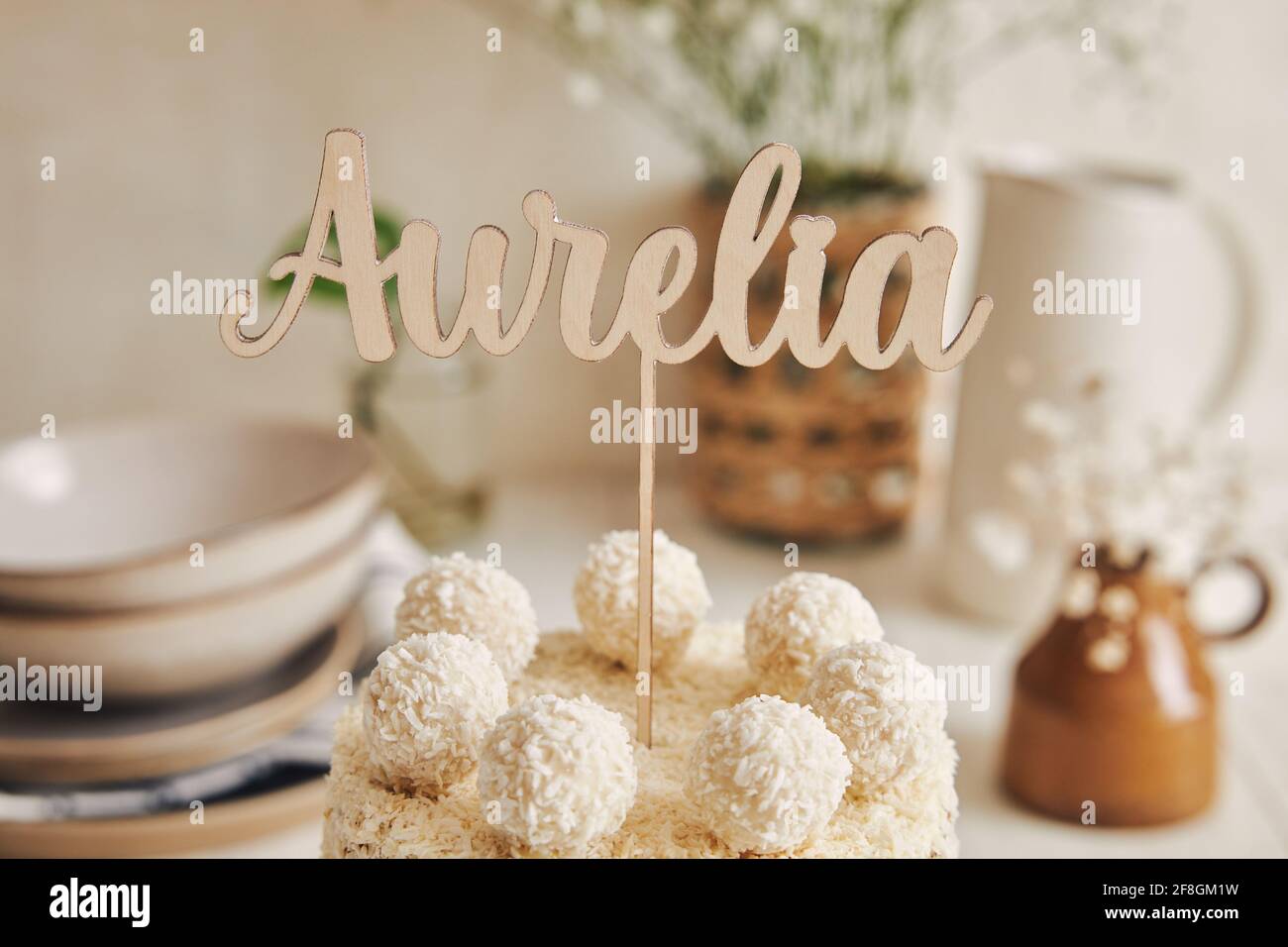 Closeup shot of a cake topper saying "Aurelia" on a cake with coconut ...