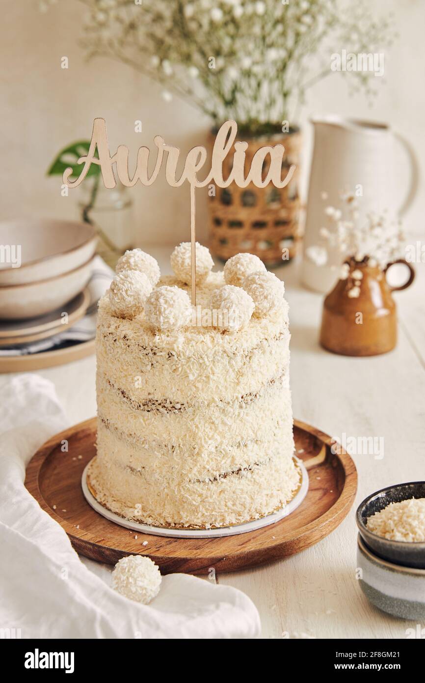 Vertical shot of a white birthday cake for "Aurelia" with coconut ...