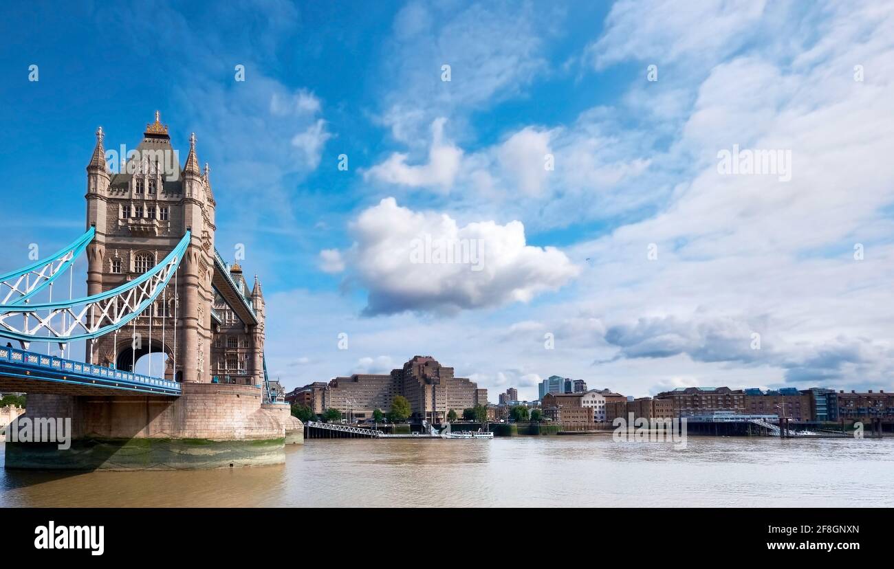 Tower Bridge on a bright sunny day with blue sky and clouds. Calm water ...
