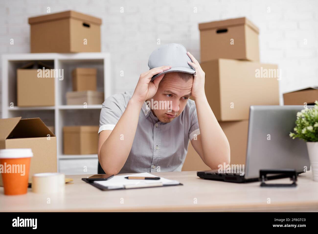 Sad, bored or tired postman in post office with boxes behind of him ...