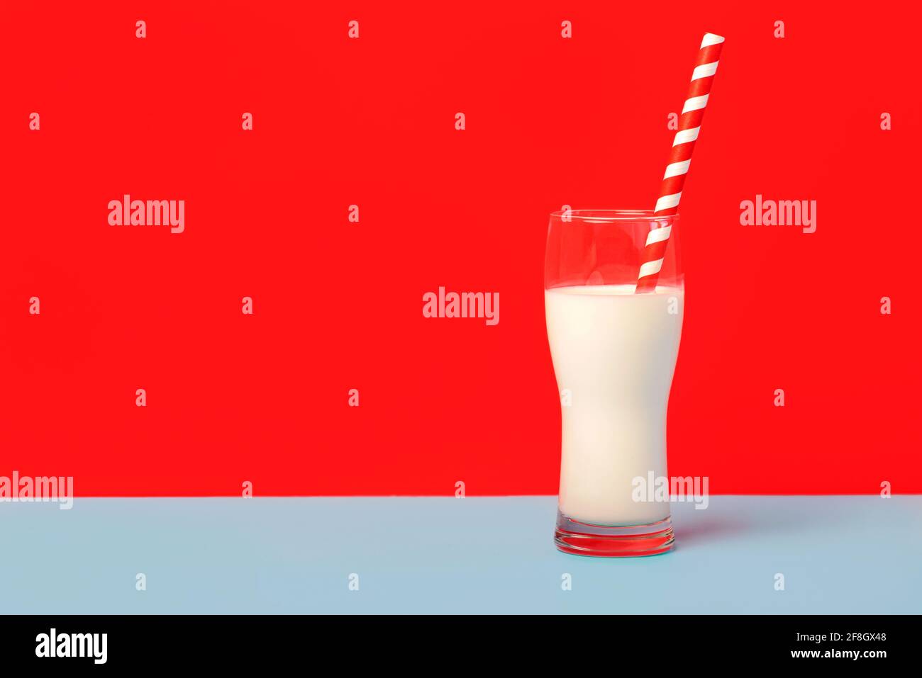 Glass of milk and a red and white drinking straw on red and blue ...