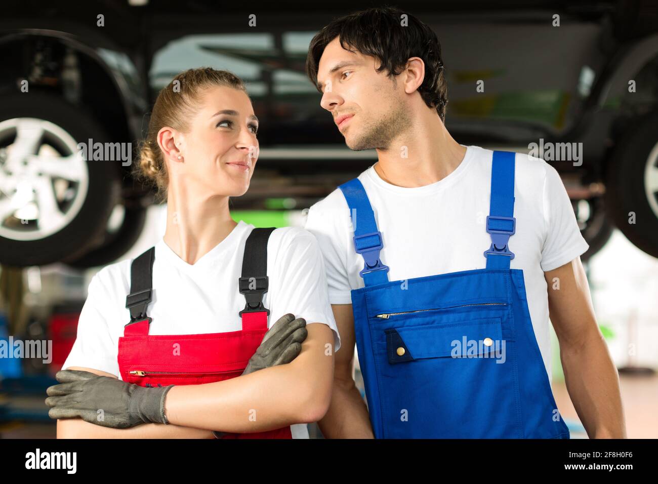 Young woman and man in blue overall - mechanic - stand with in front of ...