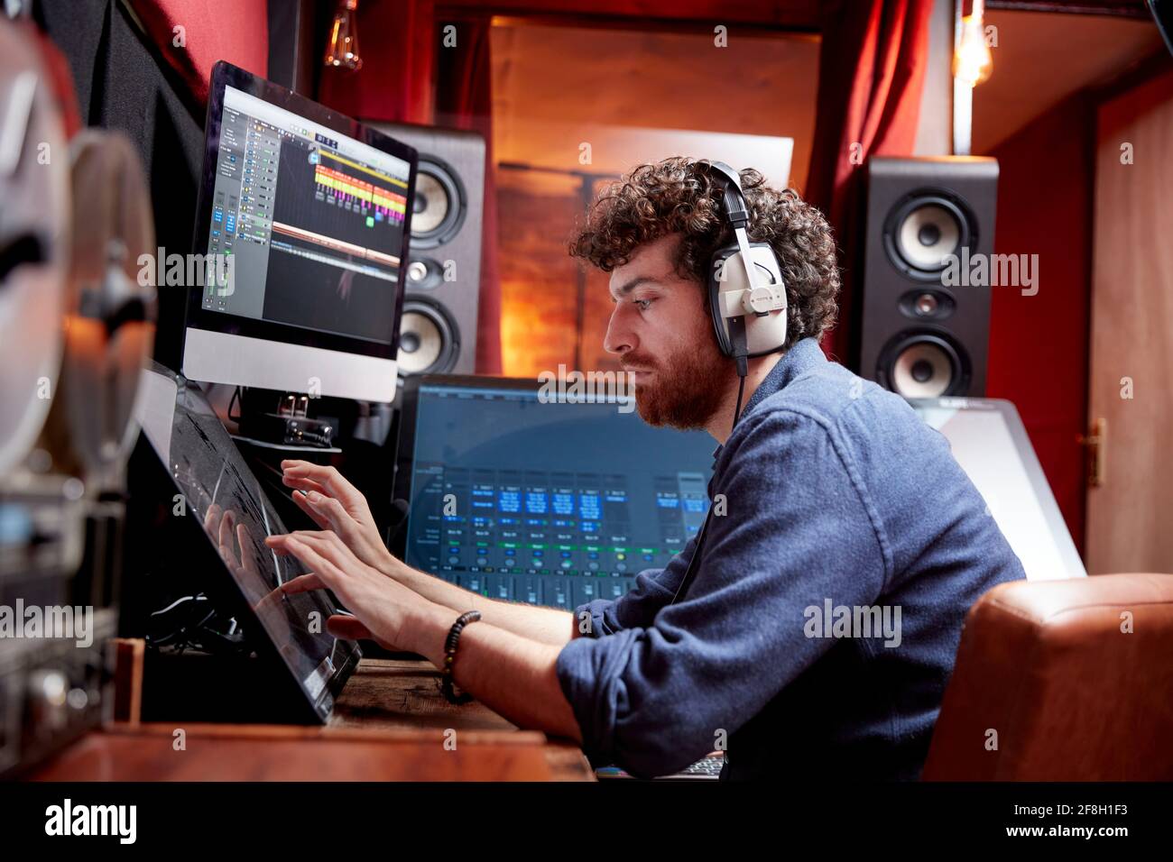 Man working in music studio using computer wearing head phones Stock ...