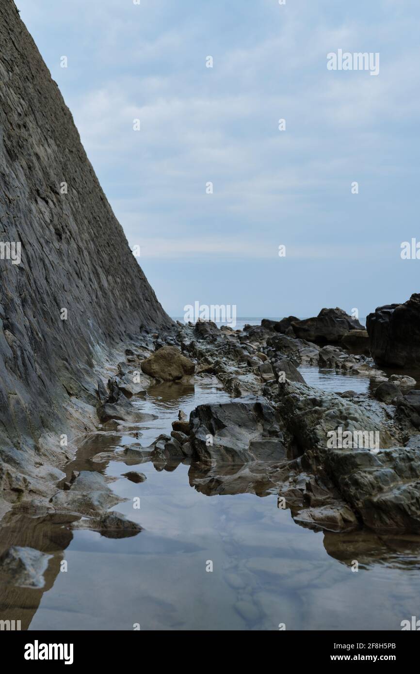Rocks and blue sea. Side view of a huge mountain facing the ocean ...