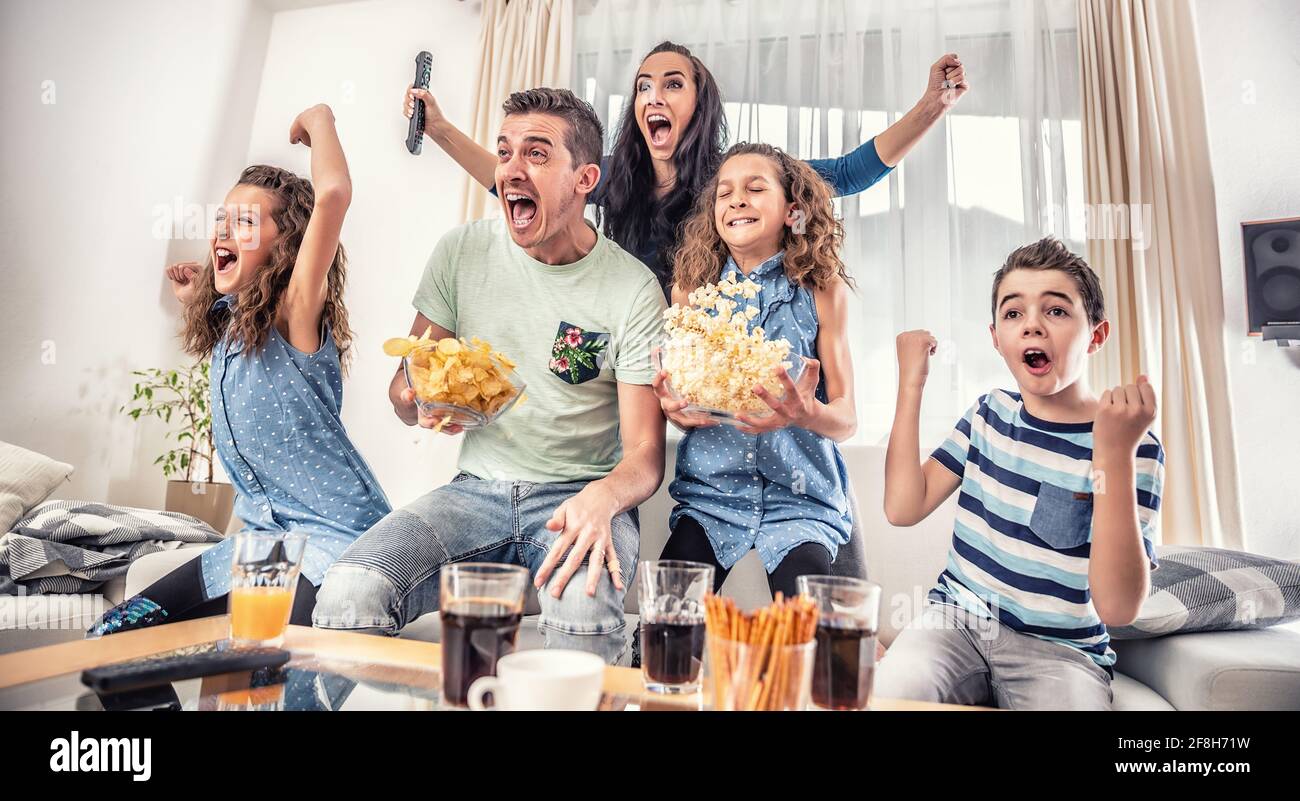 Family watching sports match on tv at home, cheering and shouting goal ... Family watching sports match on tv at home, cheering and shouting goal ...