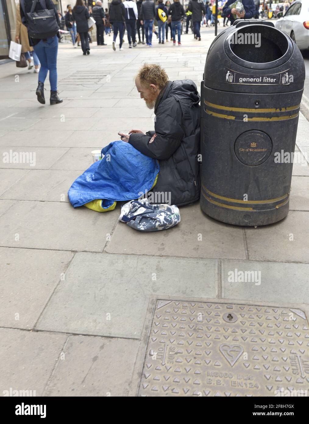 London, England, UK. Homeless man in Oxford Street on his mobile phone ...