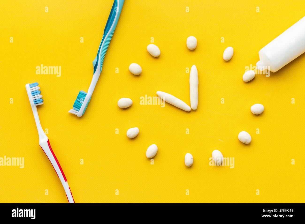 Morning routine concept. Clock made of toothpaste with toothbrushes ...