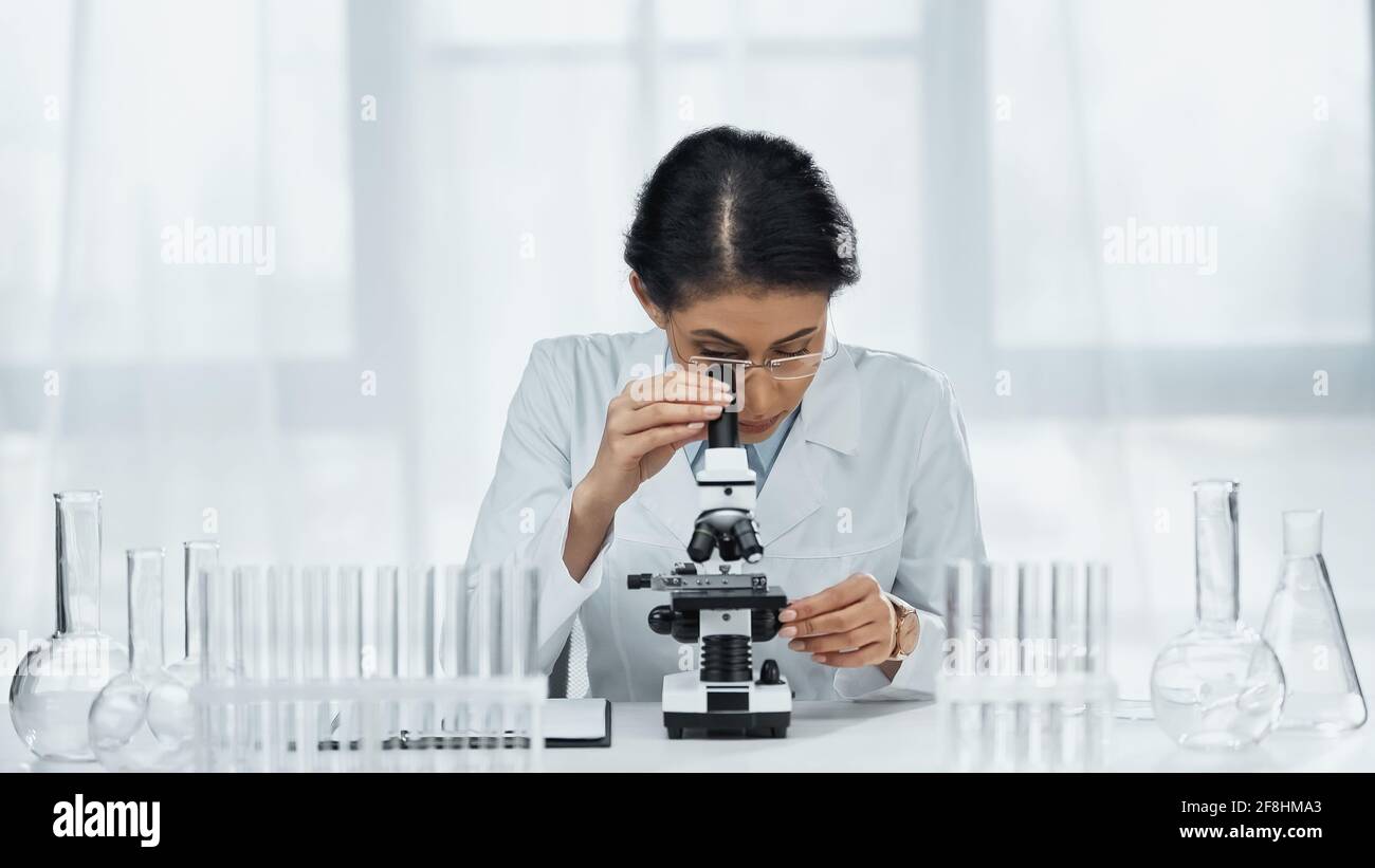 african american scientist in glasses looking through microscope in lab ...