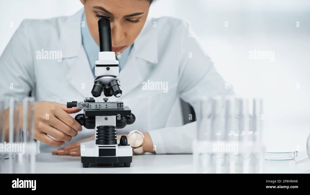 african american scientist in glasses looking through microscope in ...