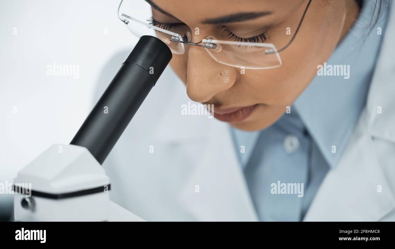 african american scientist in glasses looking through microscope in ...