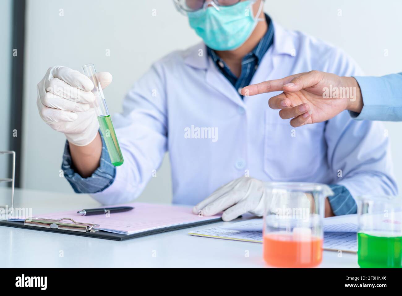 science, The scientists holds the green tube in the hand.beakers are on ...