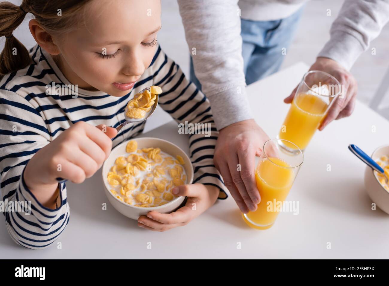 girl eating corn flakes near father and glasses of orange juice Stock ...