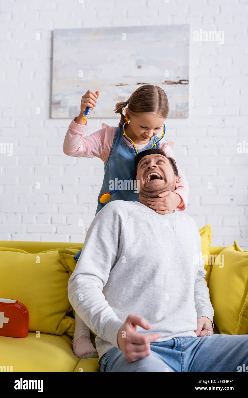 man shouting while pretending scared near daughter holding toy syringe ...