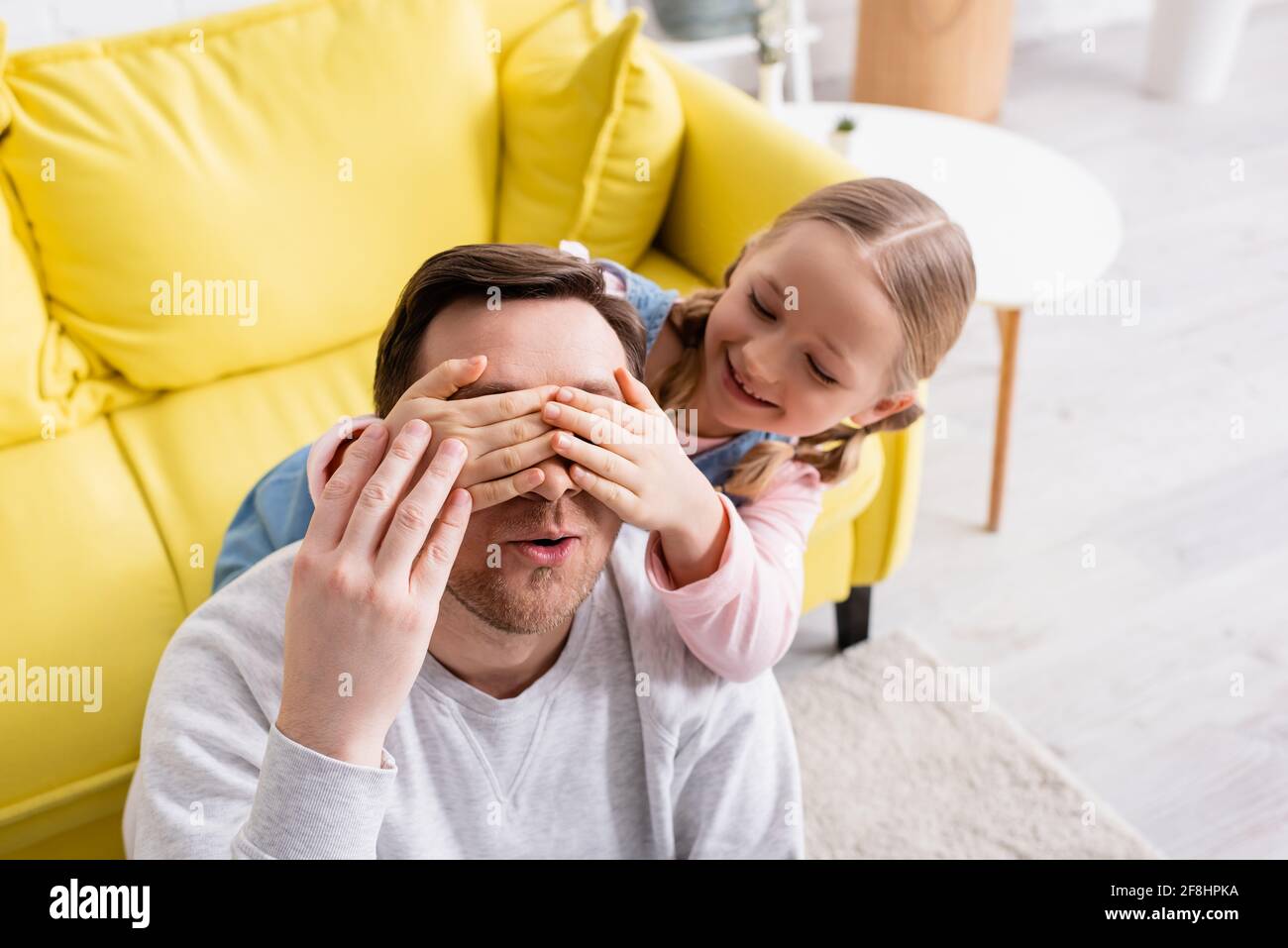 cheerful girl covering eyes of father while playing guess who game ...