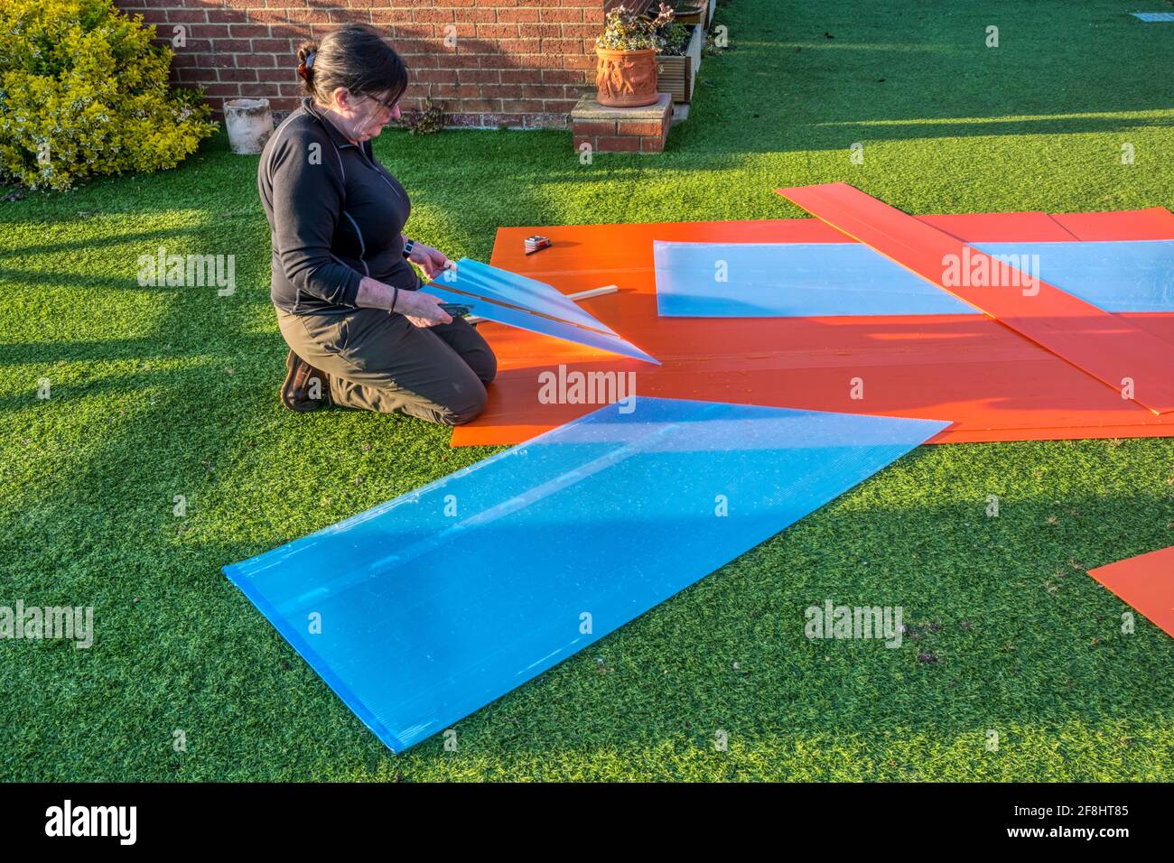 Woman cutting polycarbonate sheets to replace broken glass in ...