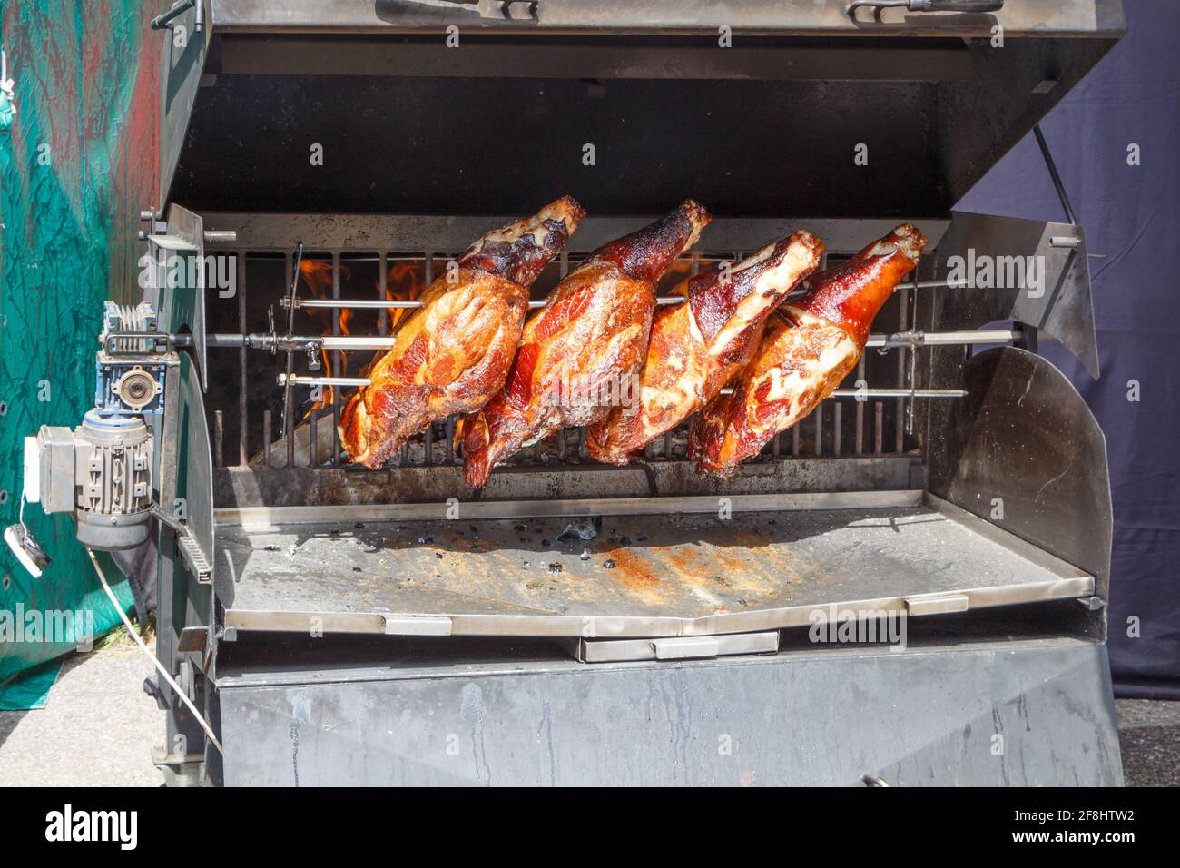 Four hams roasted by wood fire on a spit Stock Photo - Alamy