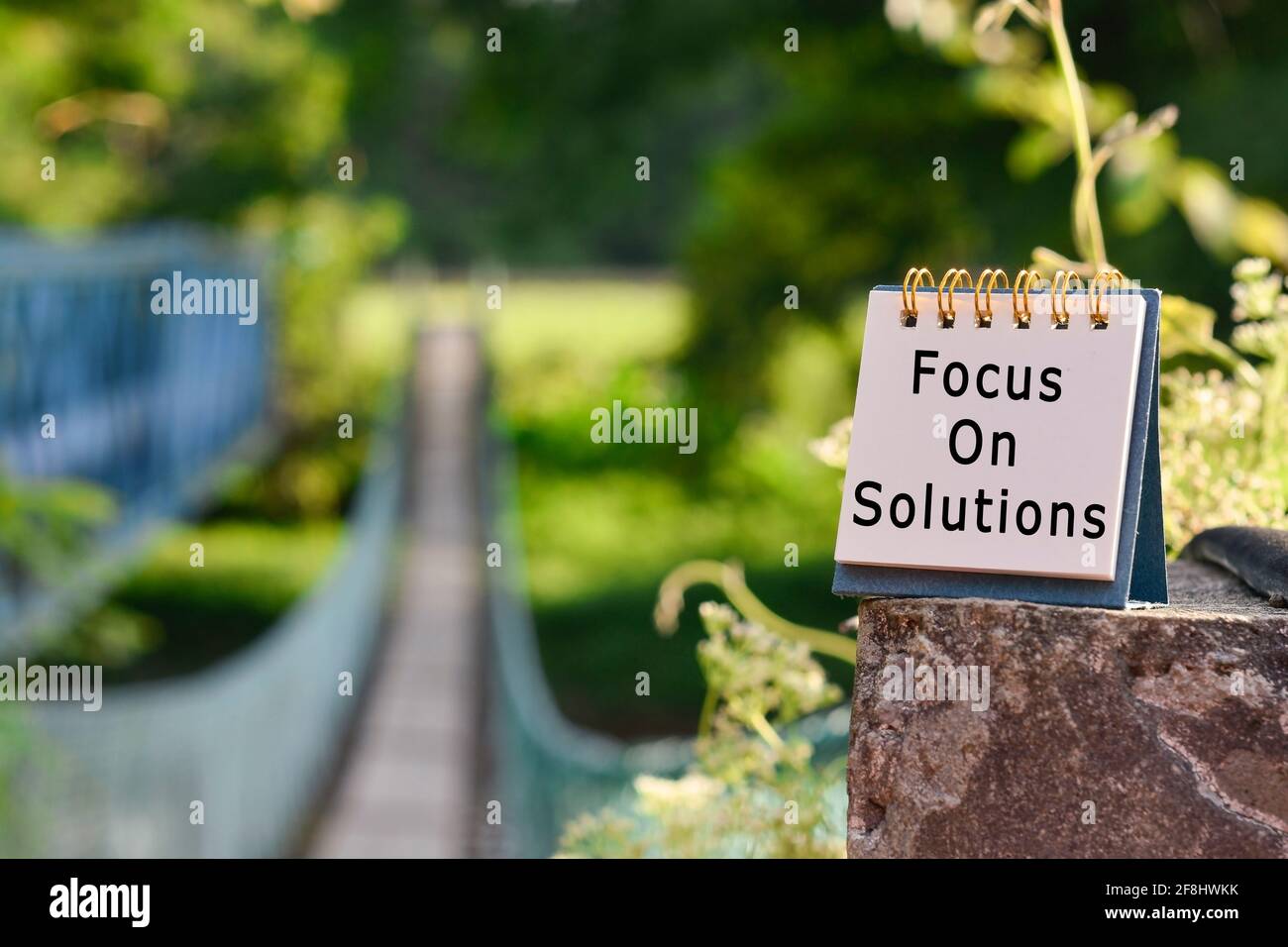 Text written on white note with blurred background of hanging bridge ...
