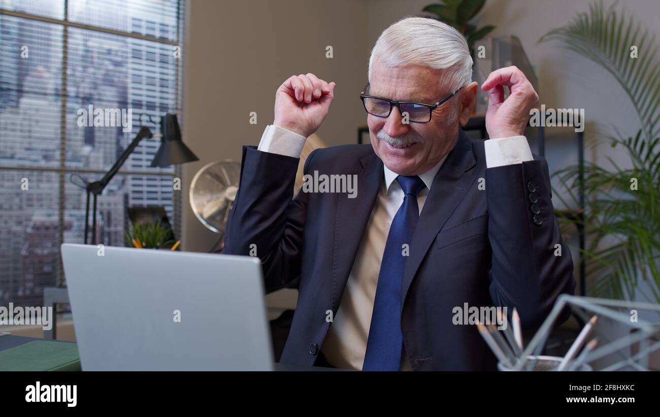 Cheerful senior business company manager working on laptop, laughing ...