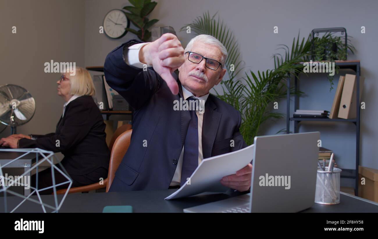 Unhappy elderly man boss making thumb down gesture expressing ...