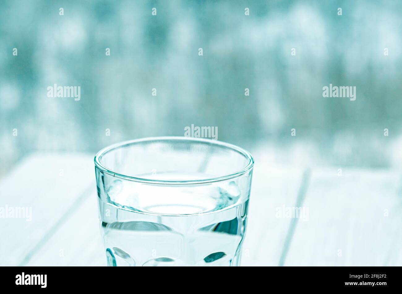 A glass with pure clear melt water stands on a white table Stock Photo ...