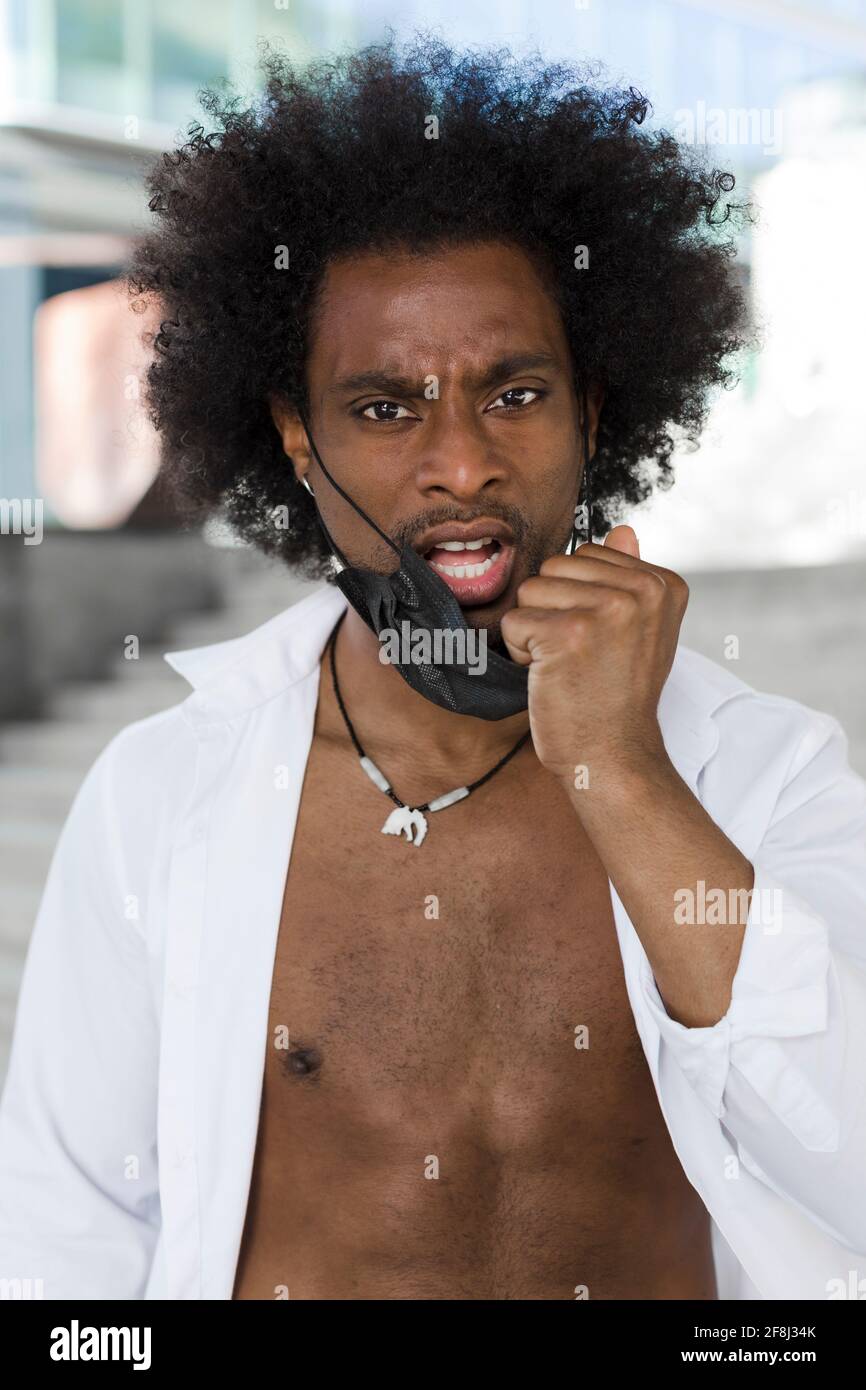 Vertical portrait of young African American man removing his face mask ...