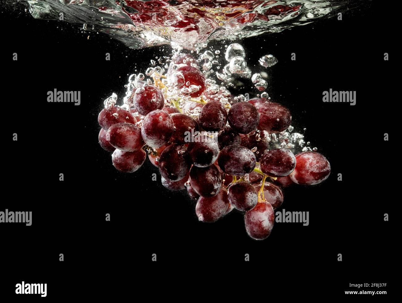 Isolated Red grapes splashing and sinking in water on black Stock Photo ...