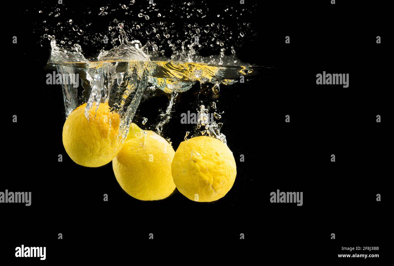 Fresh yellow lemons in water splash on black background Stock Photo - Alamy