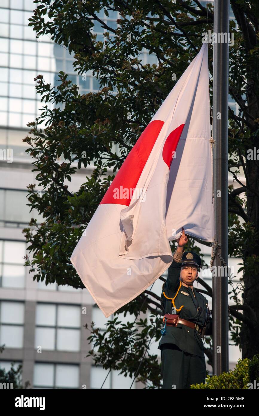 Japanese uniformed guard raising/lowering Japanese flag, Shinjuku ...