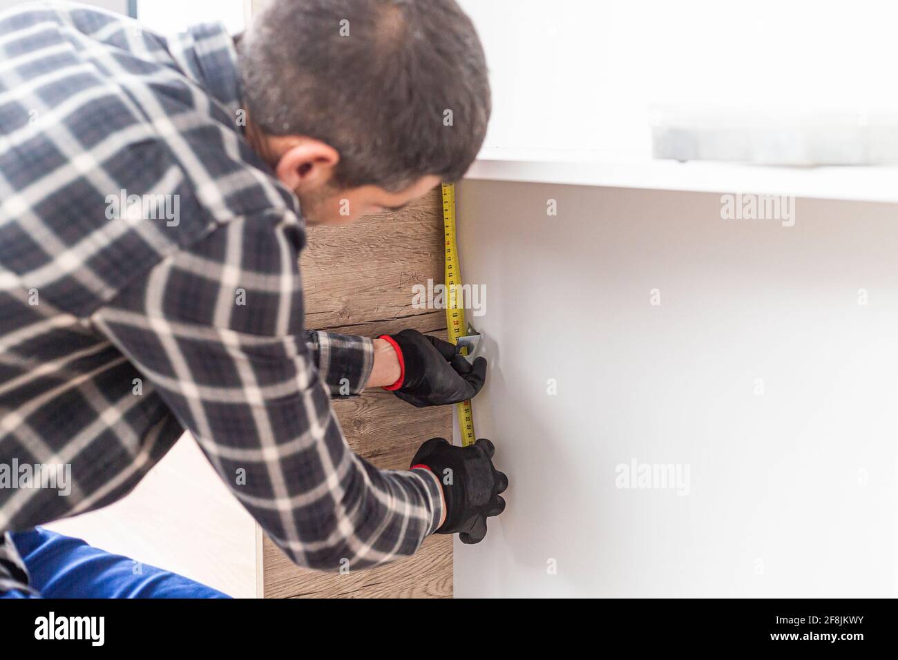 Carpenter measuring shelves in an empty apartment, where he started ...