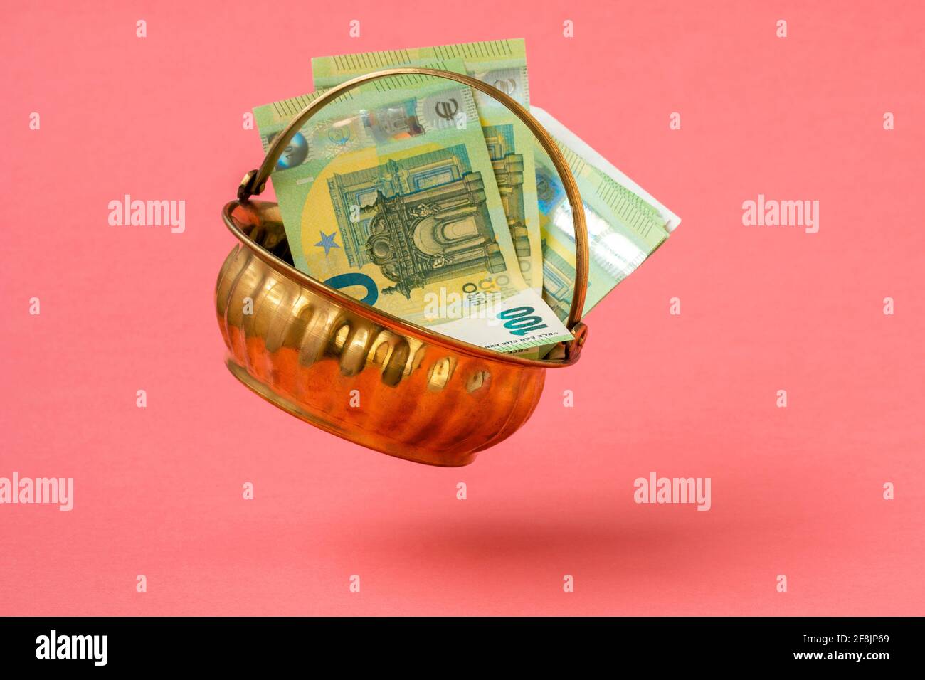 Golden pot full of Euro currency falling on pink background Stock Photo ...