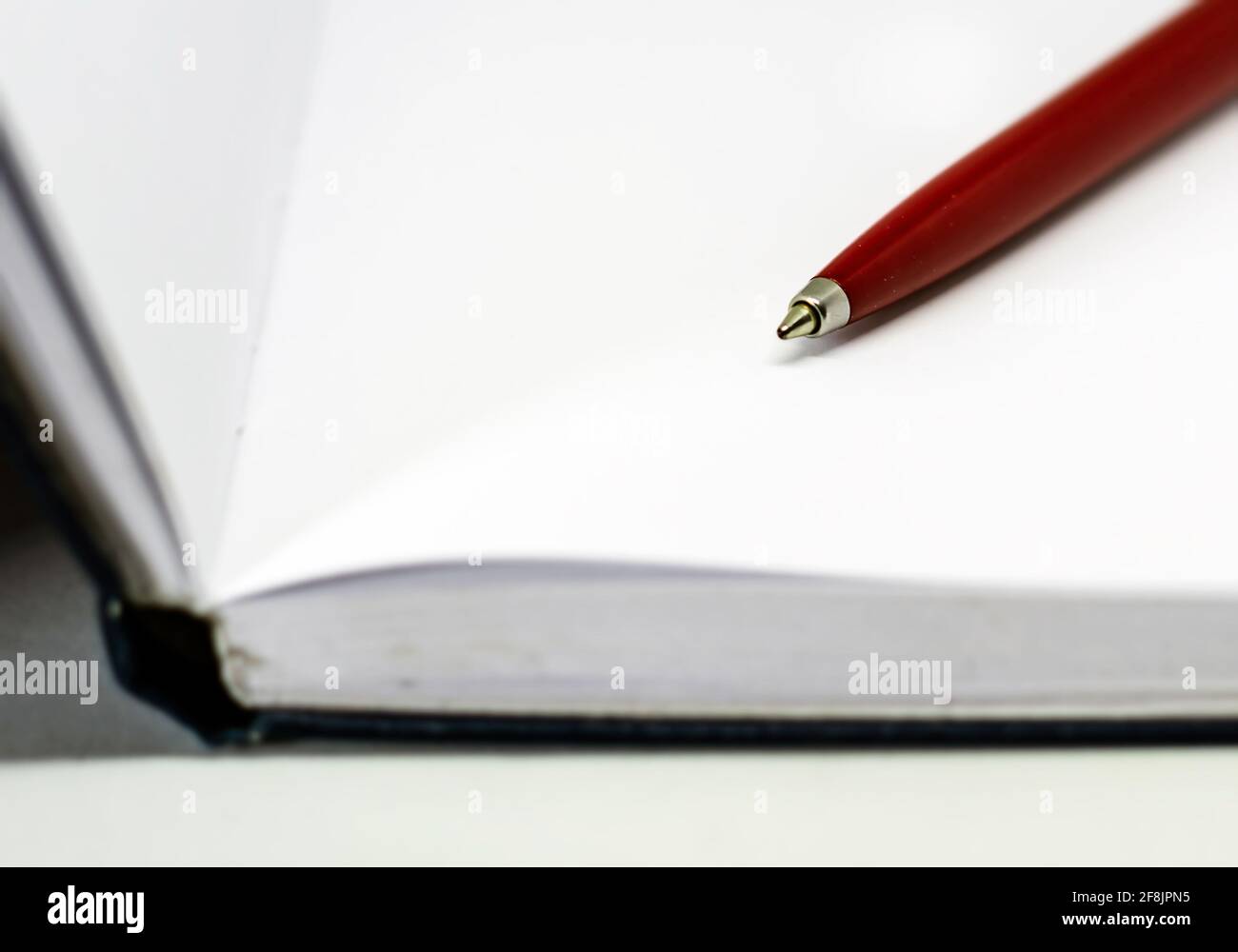Red ballpoint pen on the blank white pages of an open notebook ...
