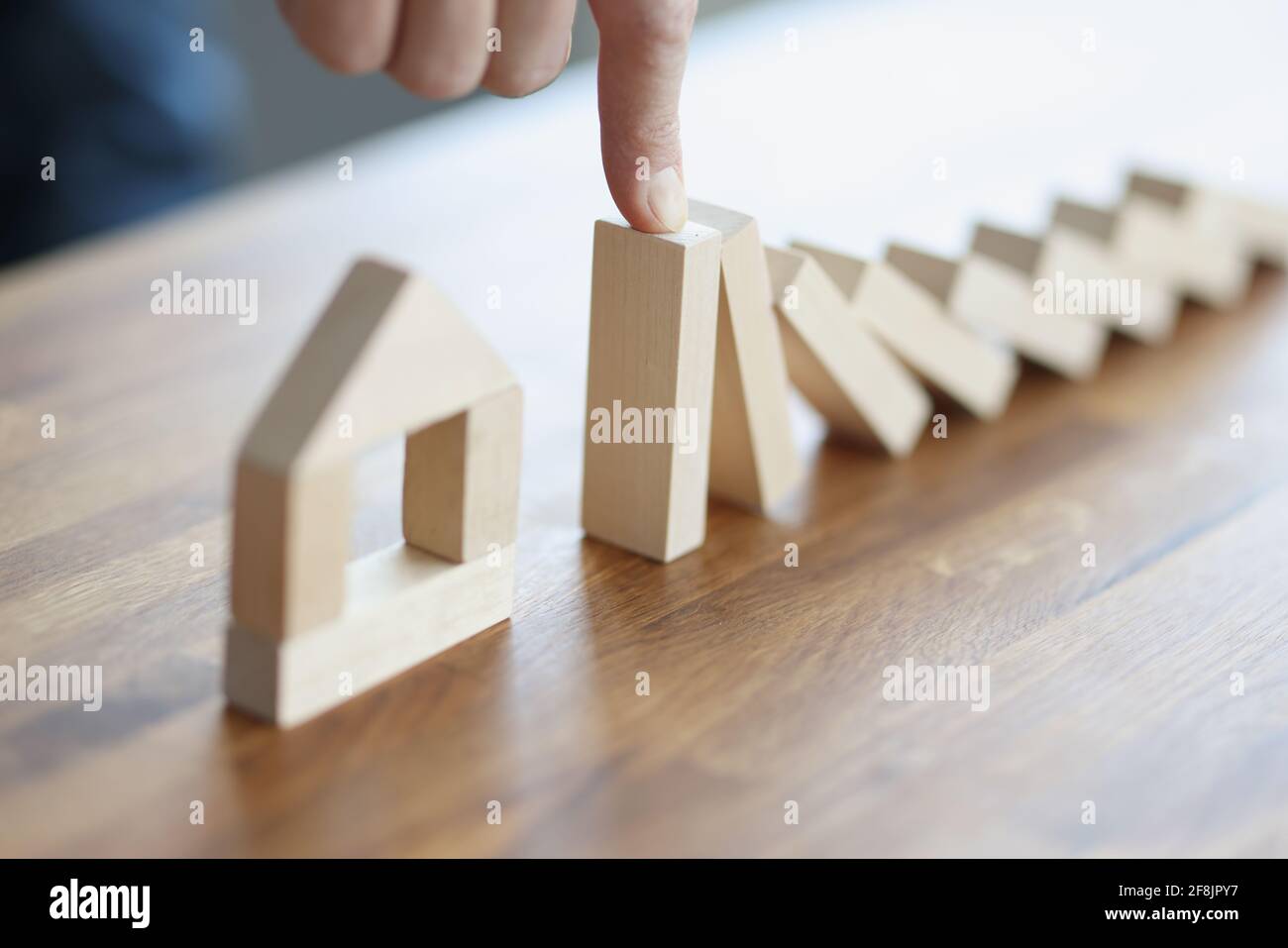 Male hand stoping falling wooden blocks on toy house closeup Stock ...
