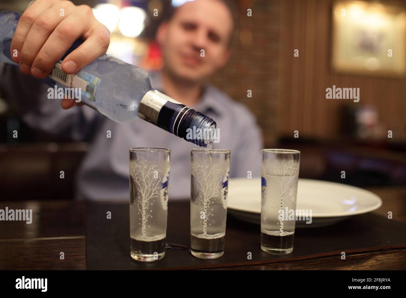 Man pouring vodka into the glasses at the pub Stock Photo - Alamy