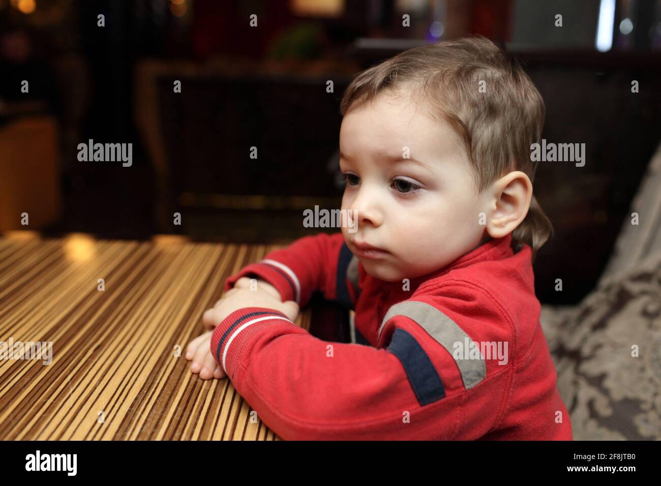 Pensive child waiting food at a cafe Stock Photo - Alamy