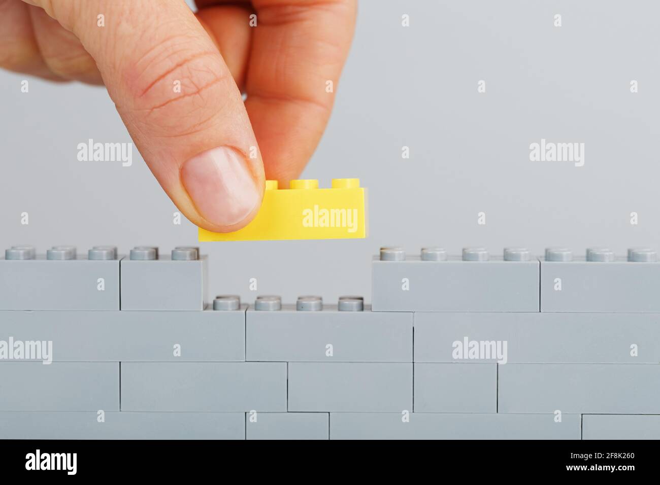 The hand puts the last yellow brick on the gray wall from the ...
