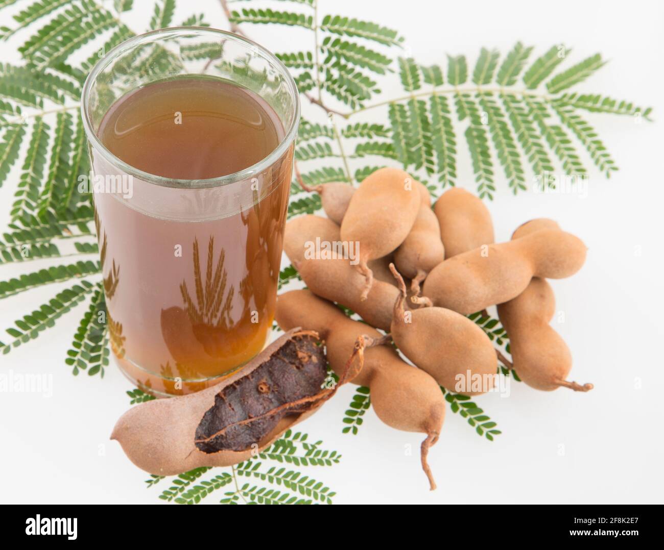 Tamarind juice in a glass surrounded by fresh ripe tamarinds ...