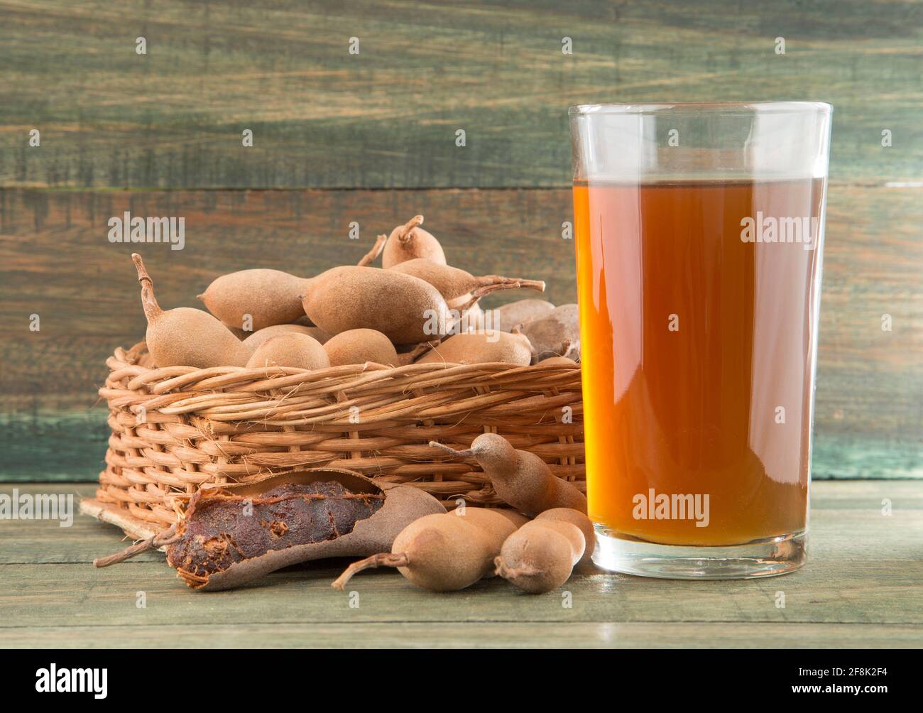 Tamarind juice in a glass surrounded by fresh ripe tamarinds ...