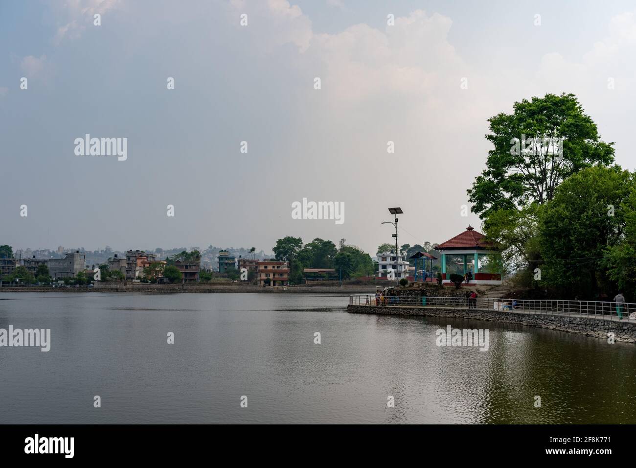 KATHMANDU, NEPAL - Apr 11, 2021: A lake in a park with a city in the ...