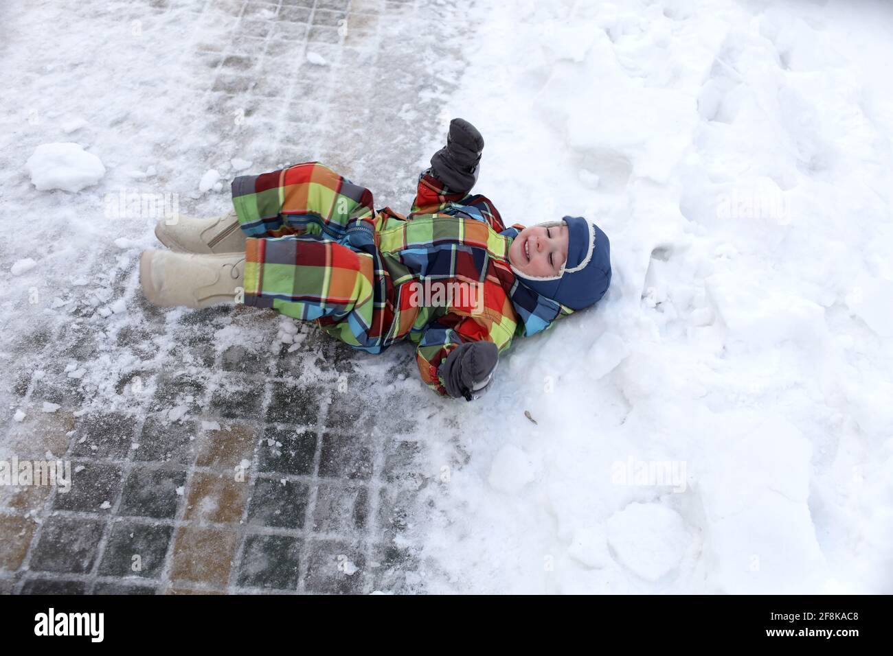 Child lying in the snow on his back Stock Photo - Alamy
