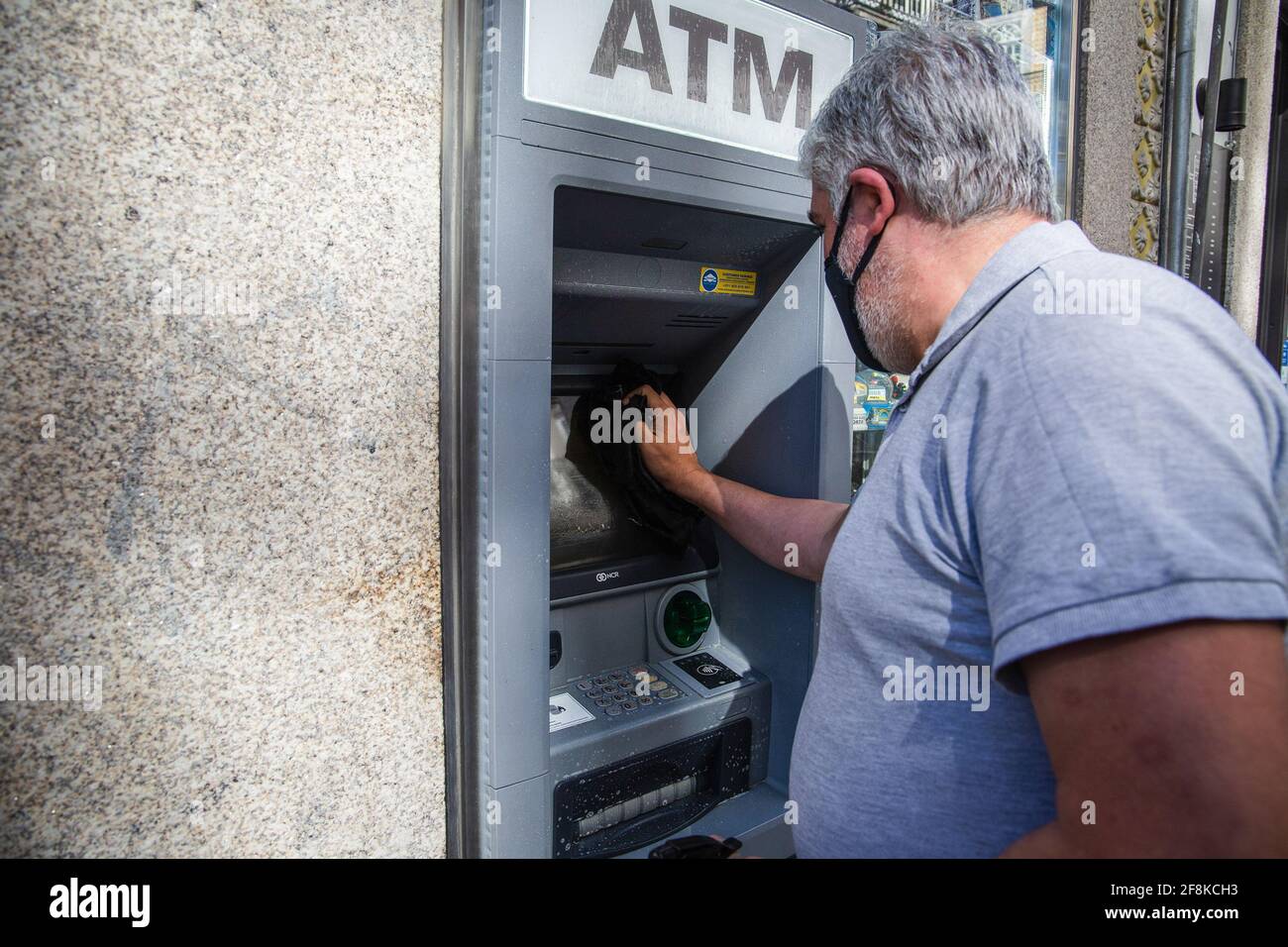 Porto, Portugal. 14th Apr, 2021. A man seen disinfecting an ATM machine ...