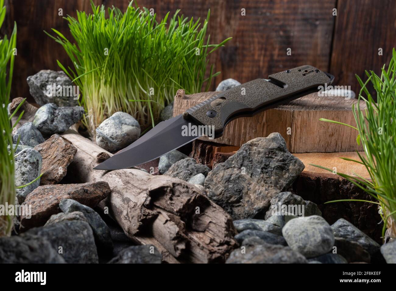 Folding army knife on stones. Knife with black blade and olive handle ...