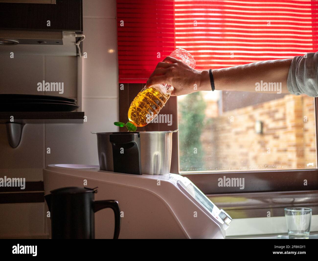 Spanish woman filling the cooking machine with extra virgin oil in her ...