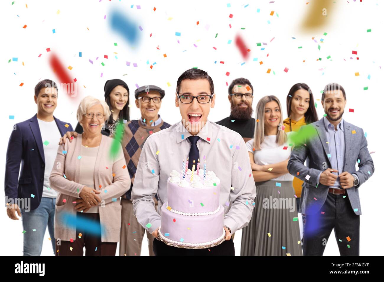 Man holding a birthday cake at a celebration with many people behind ...