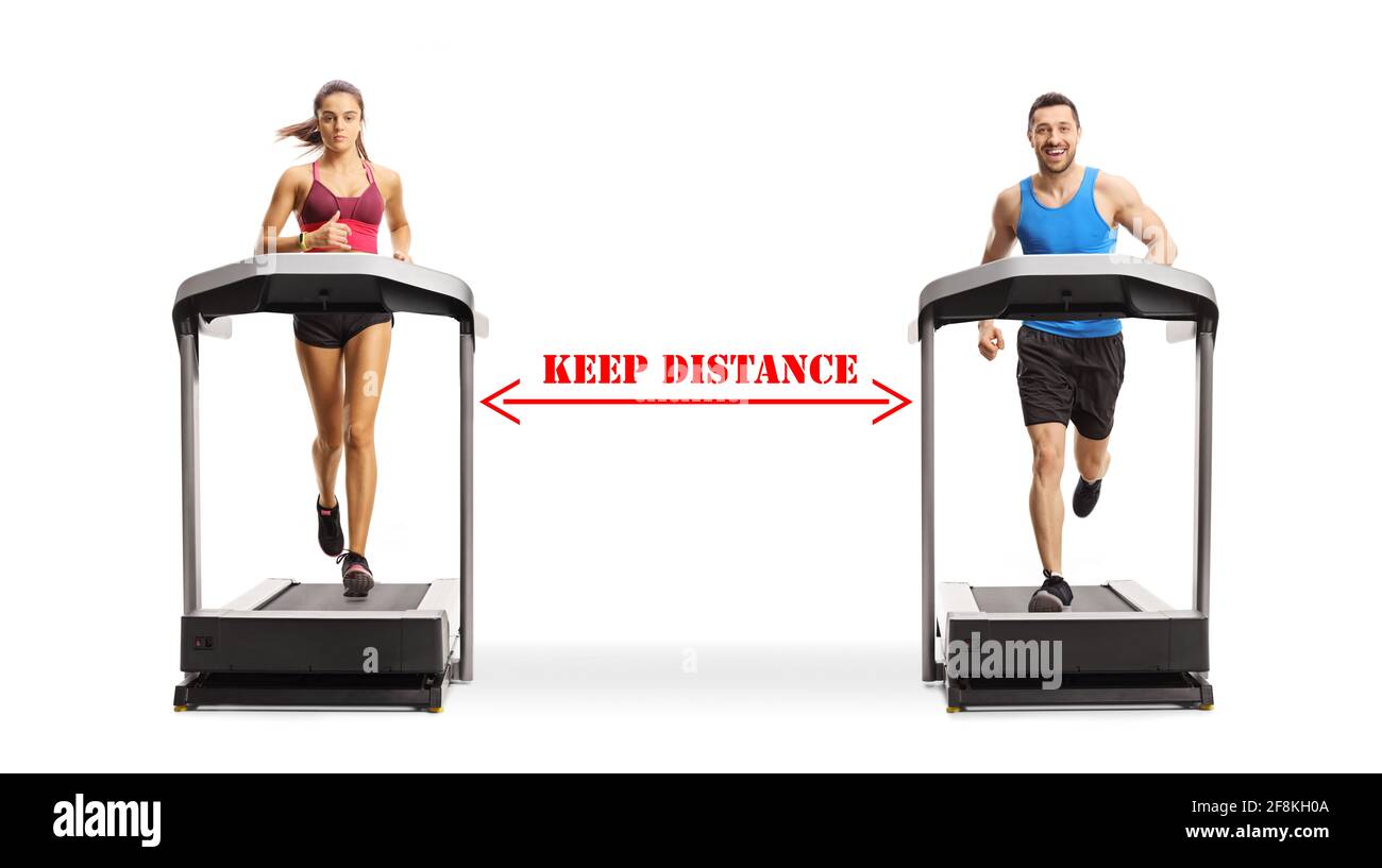 Young man and woman exercising on treadmills with sign keep distance ...