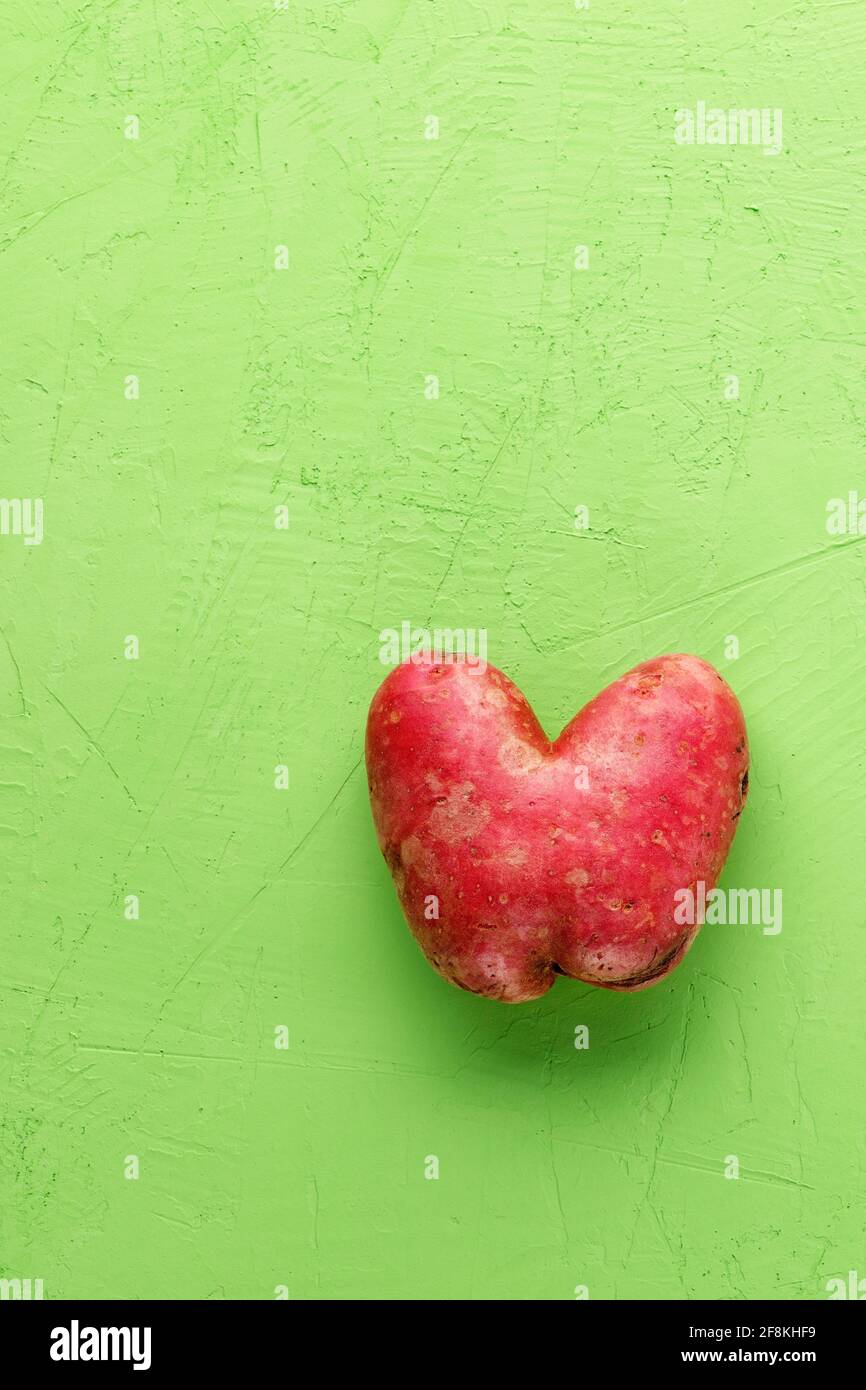 Ugly funny vegetables, heart-shaped potatoes on a green plaster ...