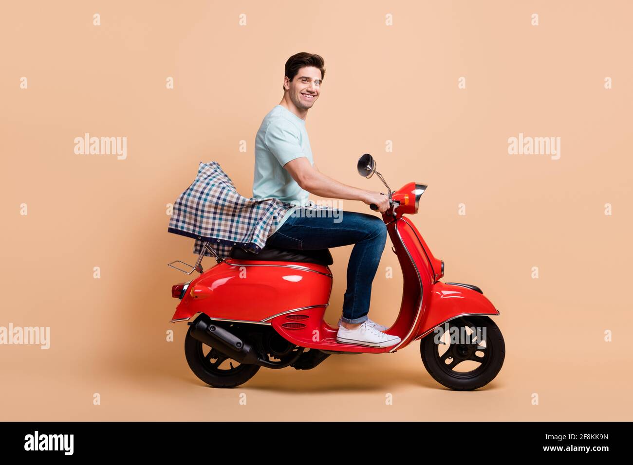 Profile side view portrait of attractive cheerful guy driving red moped ...