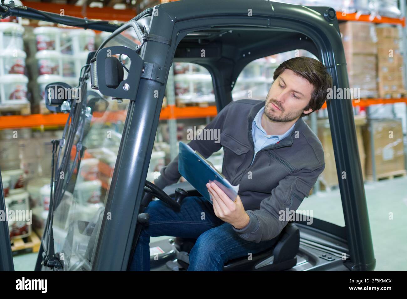 forklift driver looking at clipboard in warehouse Stock Photo - Alamy