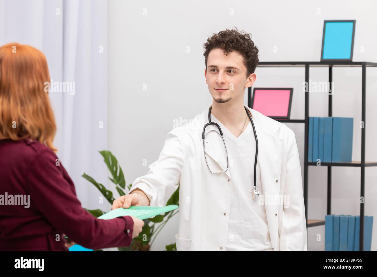 A patient with red hair gives medical records to her family physician ...