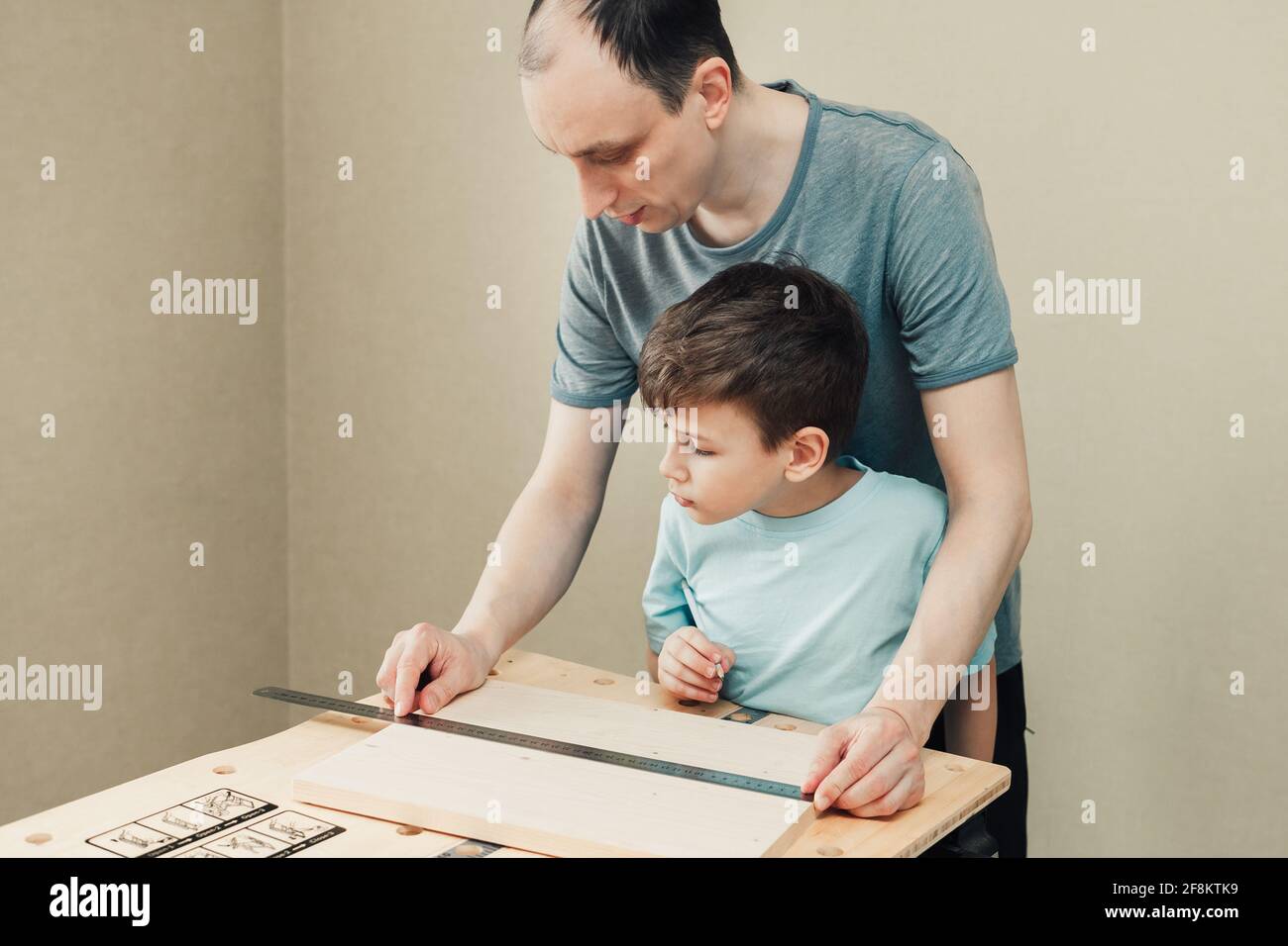Cute little boy with pencil in hand making marks on wooden plank ...
